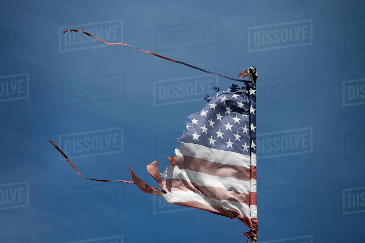 Worn and wind-torn American flag blowing against blue sky - Royalty ...