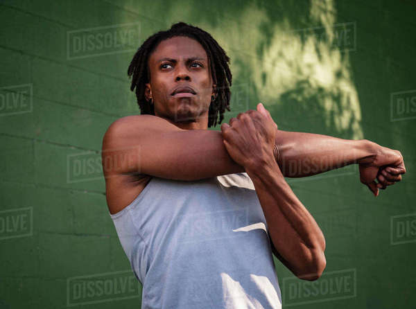 Athletic man stretching arm outdoors - Royalty-free Stock Photo | Dissolve