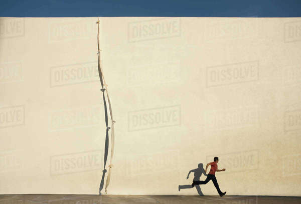 Man escaping by climbing rope over wall - Stock Photo - Dissolve