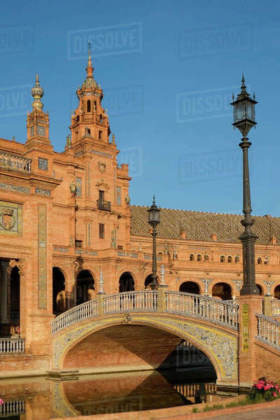 Spain, Seville, Arch bridge over canal and brick church in background ...