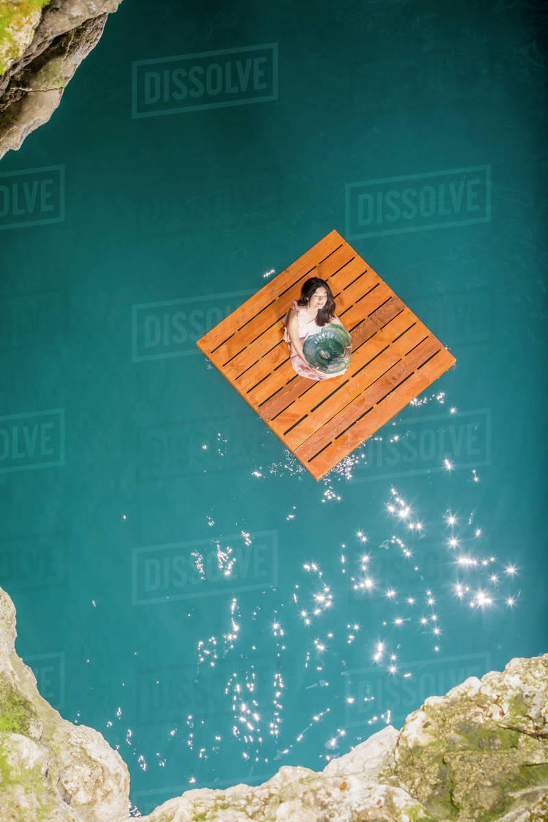 Aerial view of woman sitting on wooden raft - Royalty-free Stock Photo ...