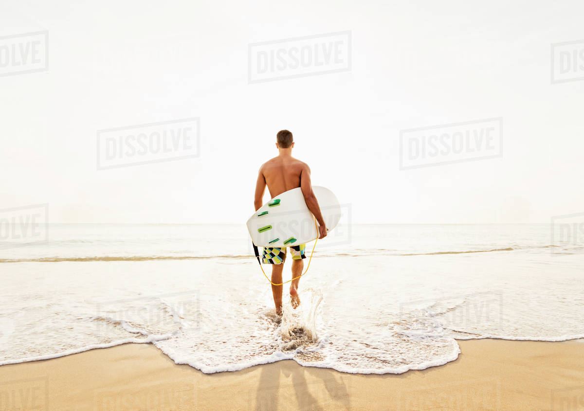 Rear view of surfer on beach - Stock Photo - Dissolve