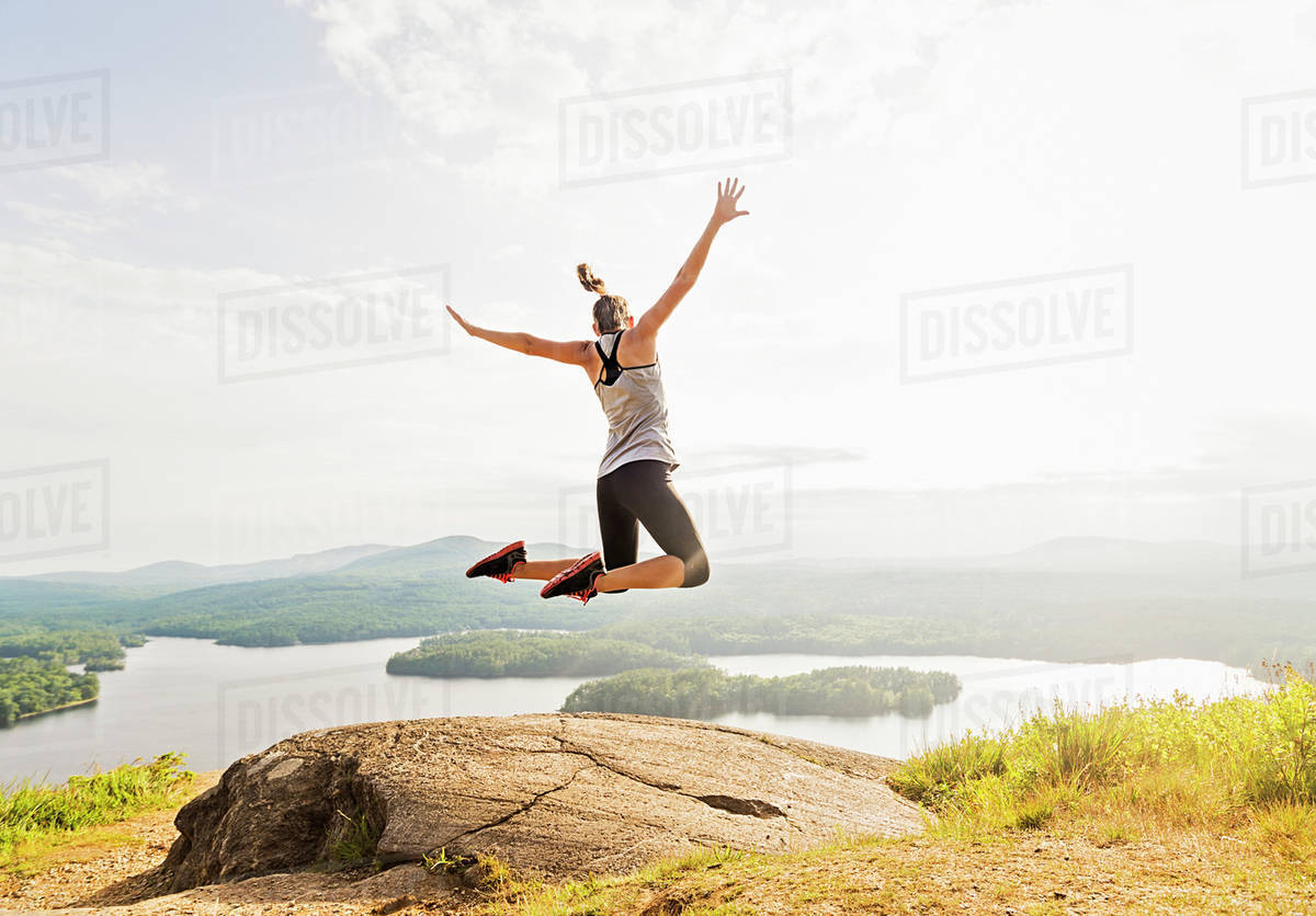 Young woman jumping over mountain top, rear view - Royalty-free Stock ...
