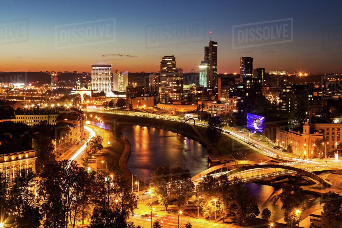 Illuminated riverfront cityscape seen from elevation on opposite bank ...