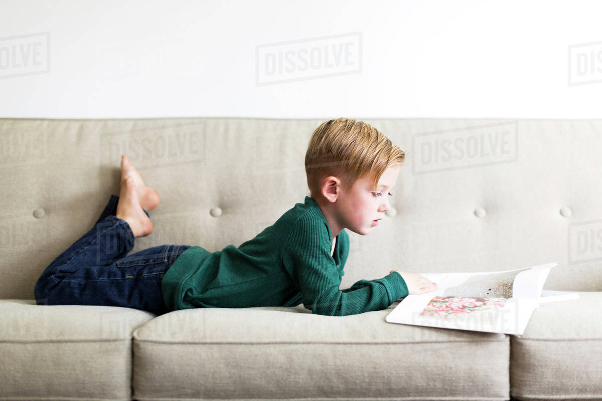 Boy (2-3) reading book on sofa - Royalty-free Stock Photo | Dissolve