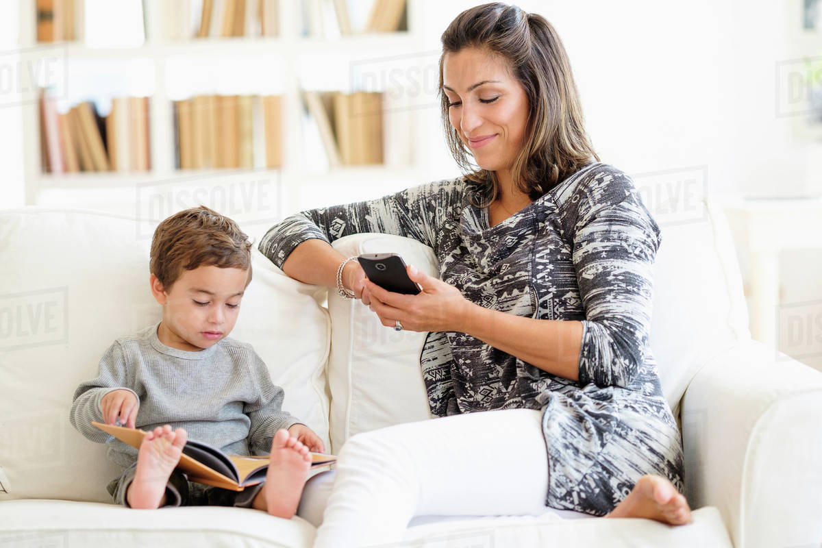 Mother texting while son (2-3) reading on sofa - Royalty-free Stock ...