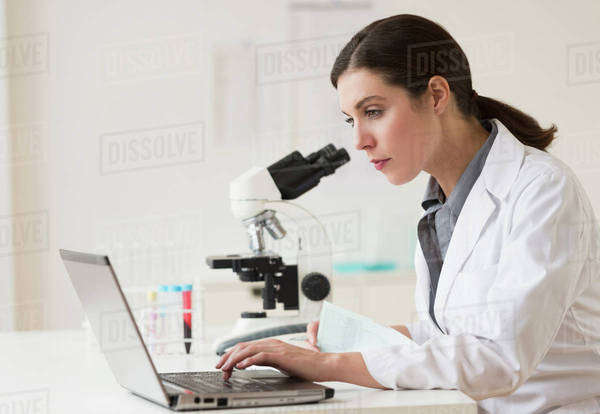 Scientist looking through microscope - Royalty-free Stock Photo | Dissolve