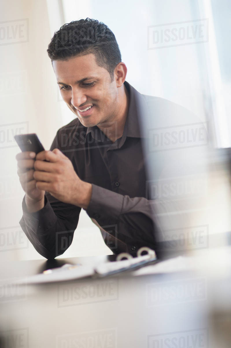 Businessman text messaging in office - Royalty-free Stock Photo | Dissolve