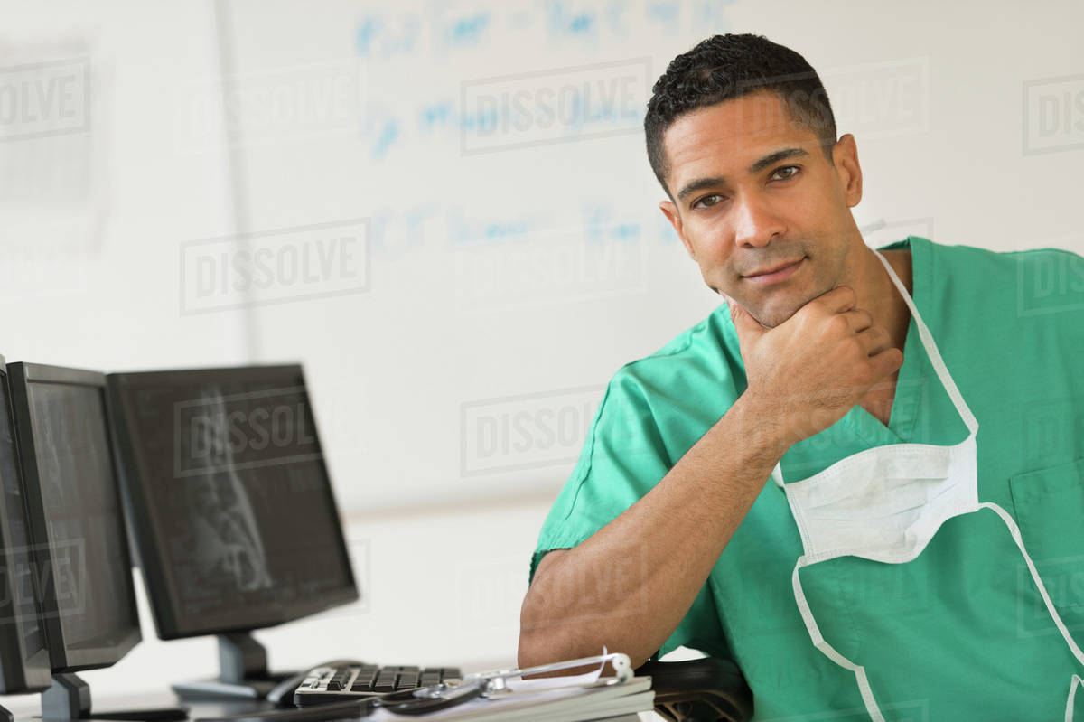 Portrait of male surgeon sitting at desk in hospital - Royalty-free ...