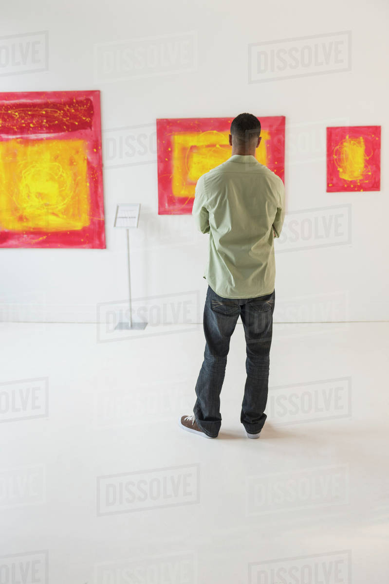 Man watching paintings in modern art gallery - Stock Photo - Dissolve