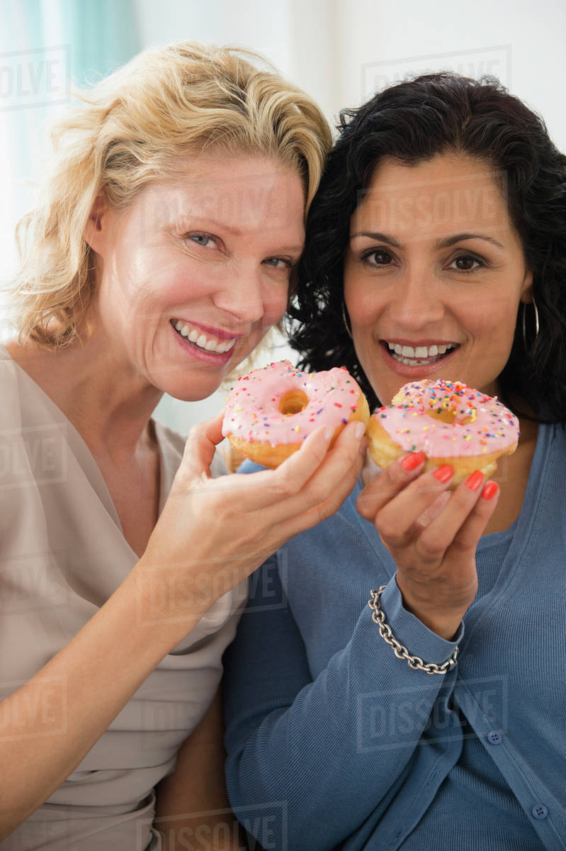 Female friends eating donuts - Stock Photo - Dissolve