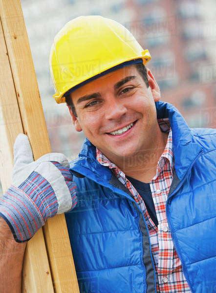 Construction worker carrying planks on construction site - Royalty-free ...