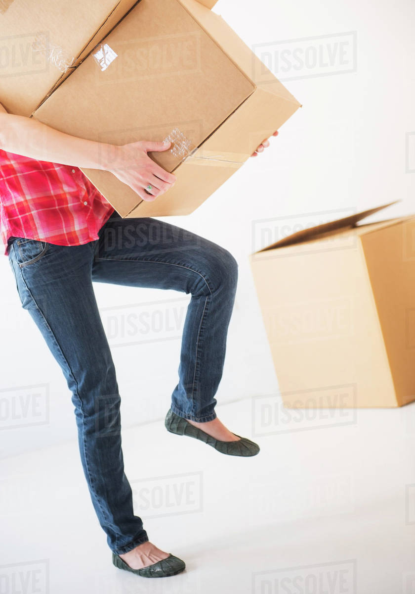 Studio shot of young woman carrying stack of boxes, low section ...