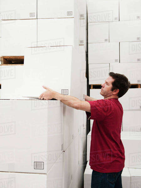 Worker stacking boxes in warehouse - Royalty-free Stock Photo | Dissolve