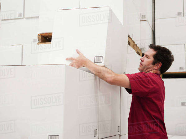 Worker stacking boxes in warehouse - Royalty-free Stock Photo | Dissolve