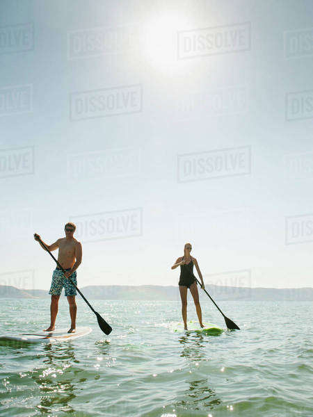 Two people standing on paddleboard - Stock Photo - Dissolve