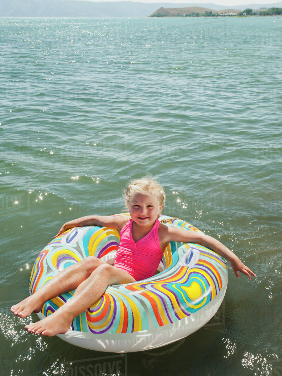 Portrait of girl (4-5) floating on water on inflatable ring - Royalty ...