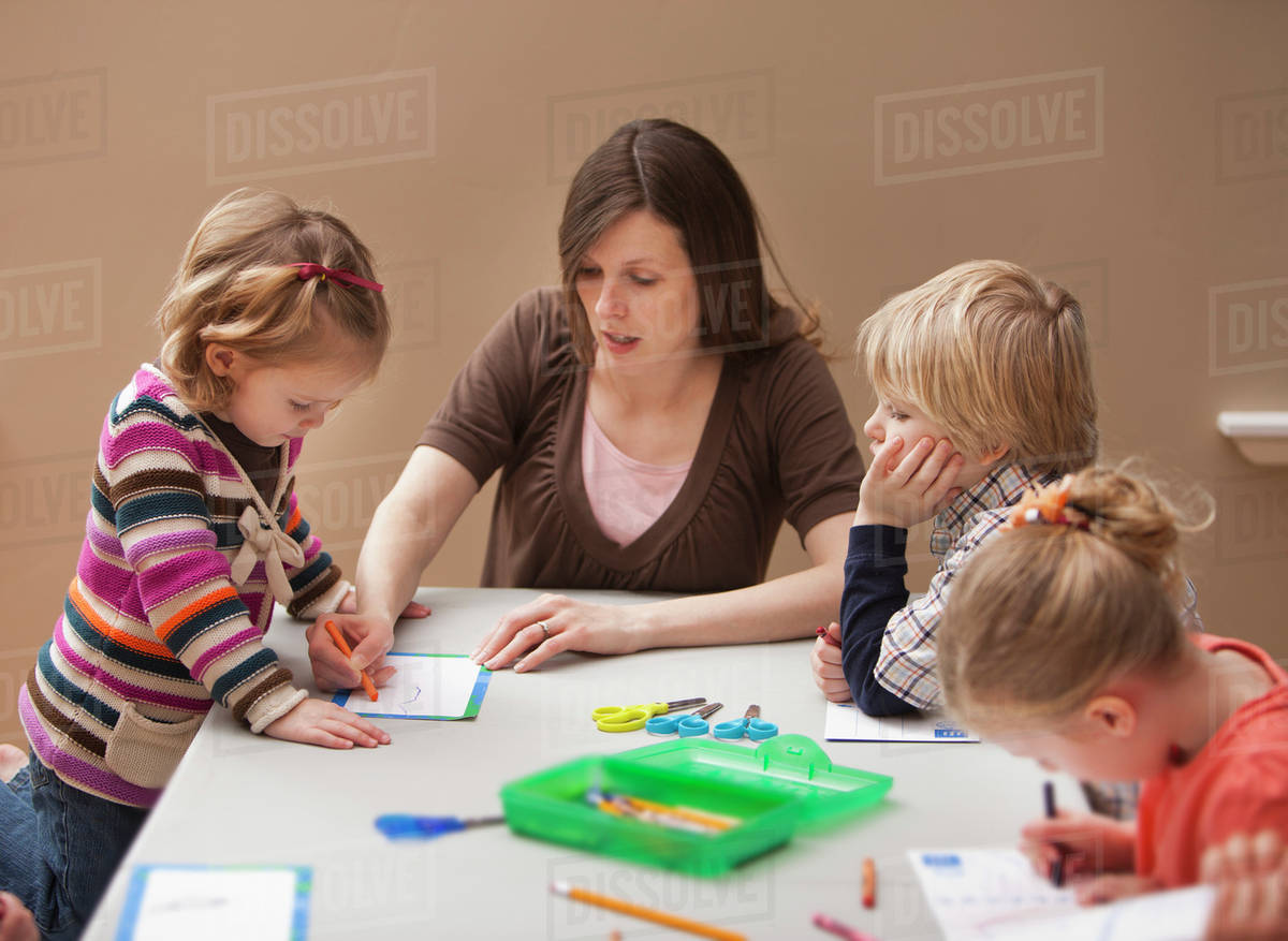 Mid adult woman teaching children (2-3, 4-5) drawing in kindergarten ...