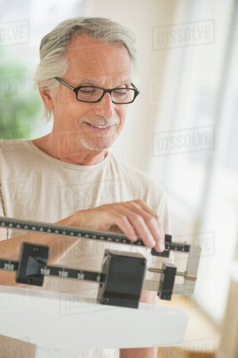 Senior man on weight scale - Royalty-free Stock Photo | Dissolve
