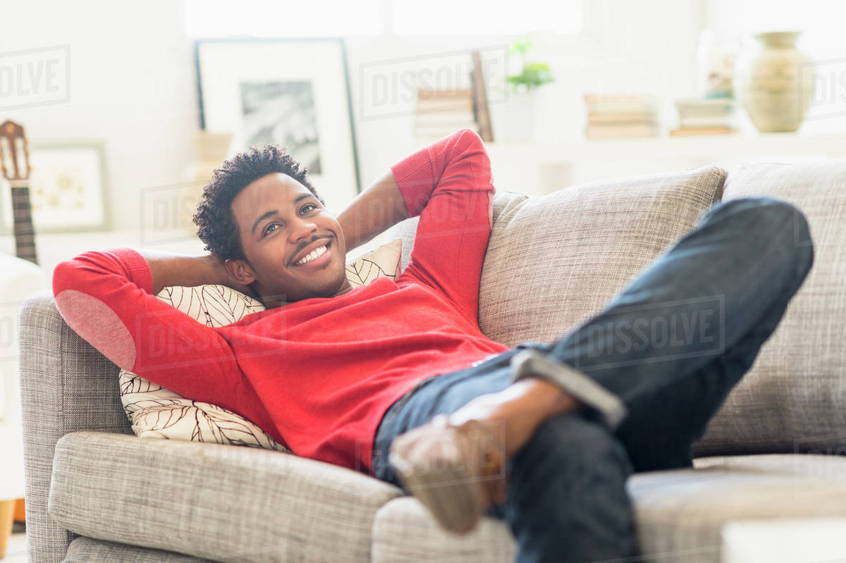 Man lying on sofa and smiling - Royalty-free Stock Photo | Dissolve