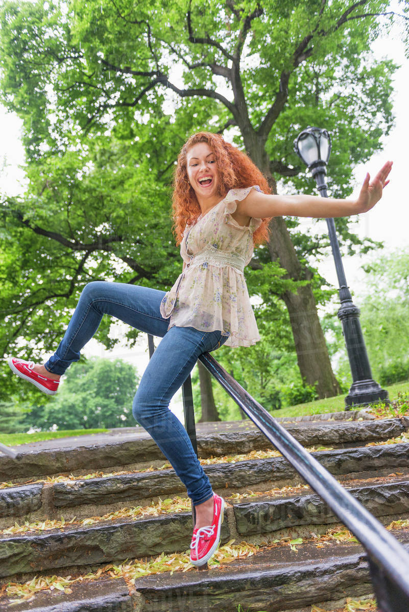 Woman sliding on railing in park - Stock Photo - Dissolve