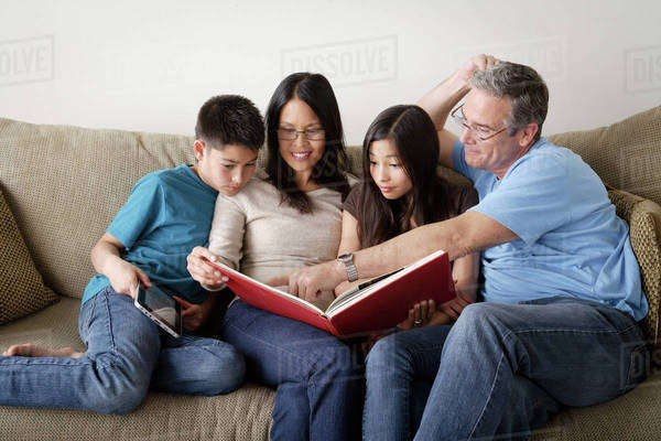 Family watching photo album together - Royalty-free Stock Photo | Dissolve