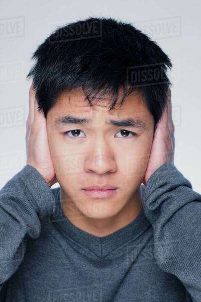 Studio portrait of young man covering ears - Royalty-free Stock Photo ...