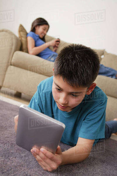 Boy using iPad lying on floor - Stock Photo - Dissolve