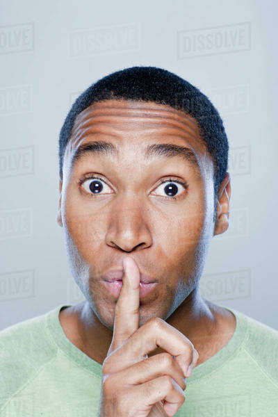 Portrait of young man with finger on his lips, studio shot - Royalty ...