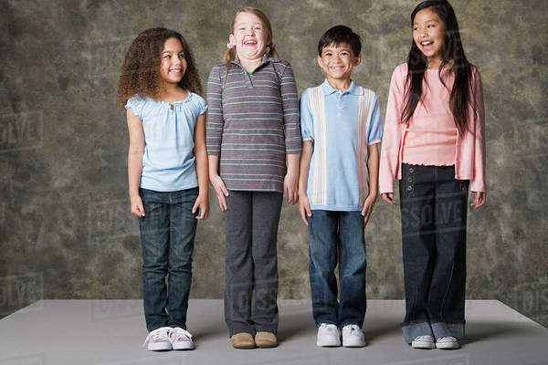 Children (8-9) laughing together, studio shot - Stock Photo - Dissolve