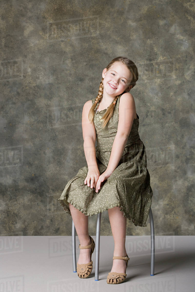 Portrait of smiling girl (8-9) sitting on stool, studio shot - Royalty ...