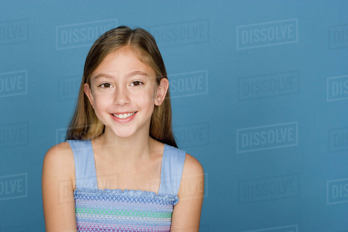 Portrait of happy girl (8-9) n blue background - Stock Photo - Dissolve