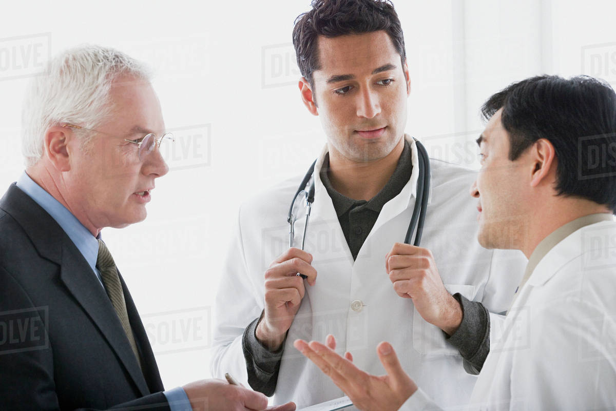 Three doctors discussing - Stock Photo - Dissolve