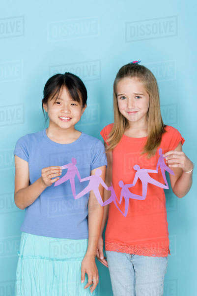 Studio shot portrait of two teenage girls holding paper chain, three ...
