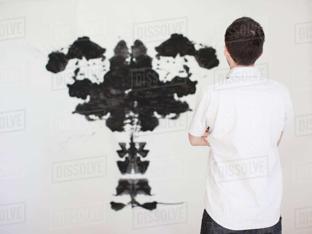 Man looking at black complex shape painted on wall - Stock Photo - Dissolve