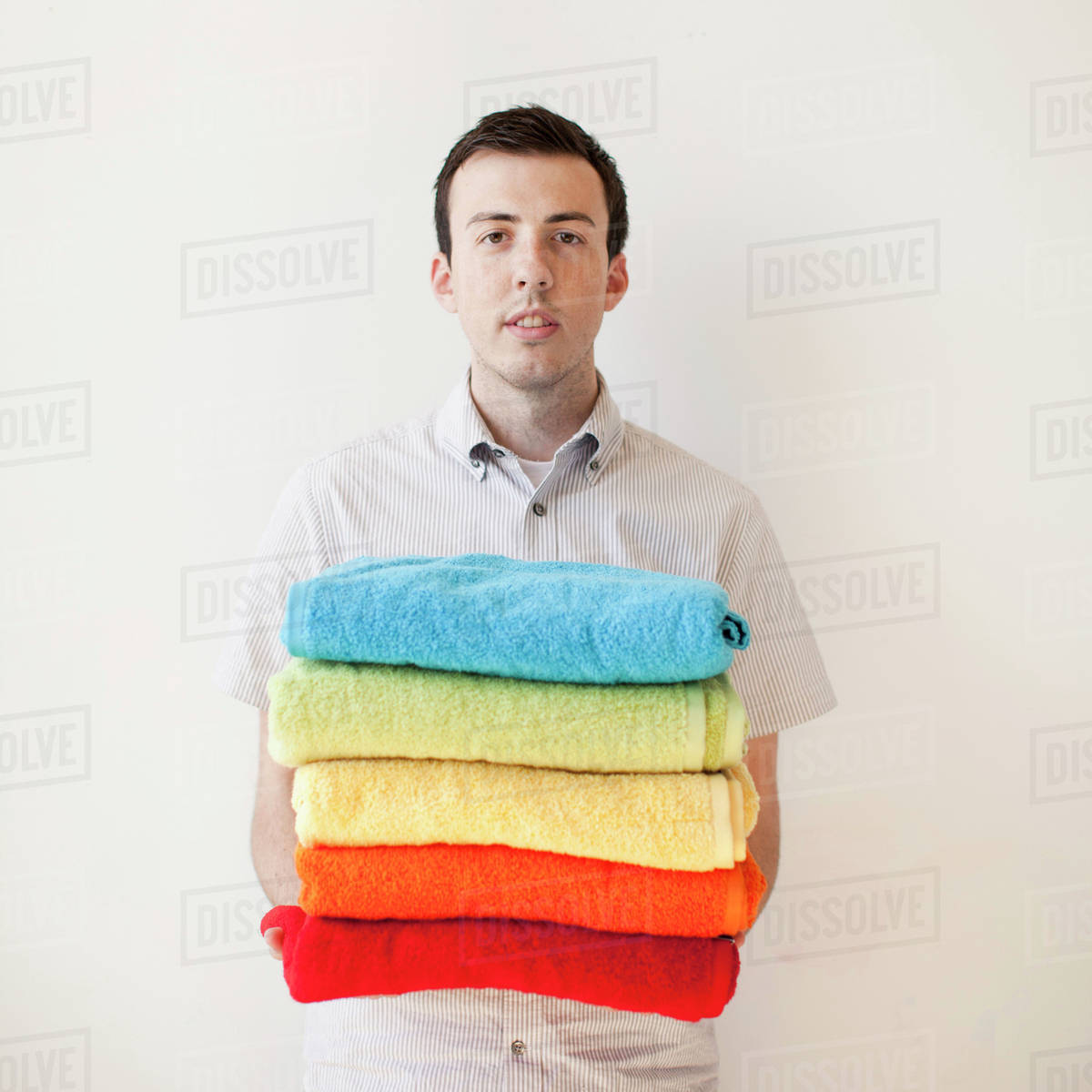 Young man holding stack of multi-coloured towels - Royalty-free Stock ...