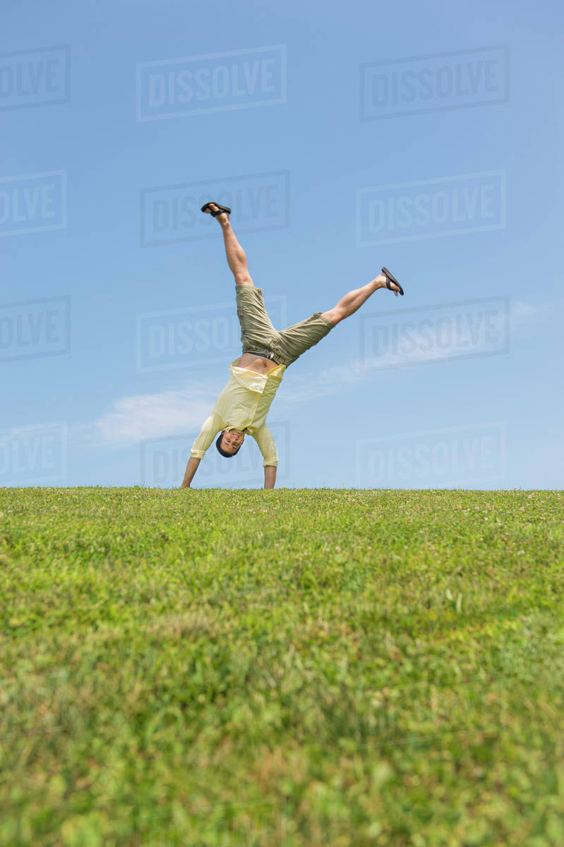 Man doing cartwheel on meadow - Royalty-free Stock Photo | Dissolve