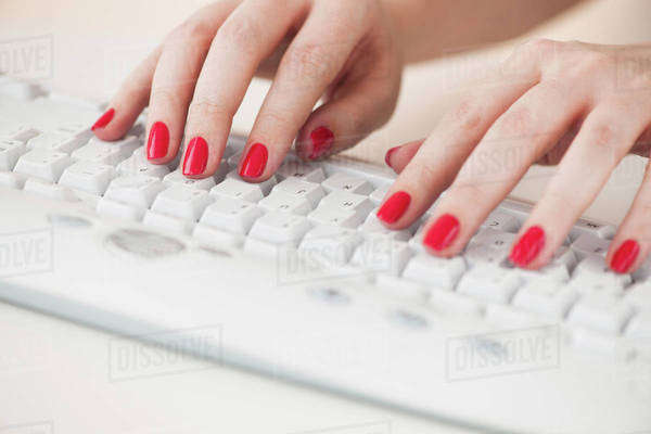 Close up of woman's fingers with red nail polish typing on computer ...