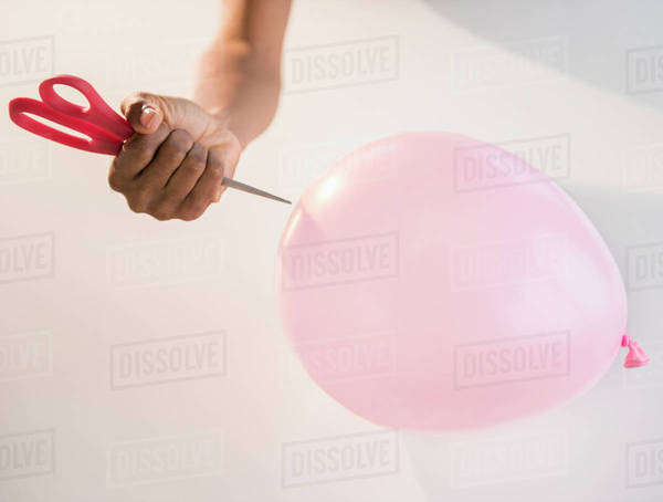 Close up of woman's hand popping balloon with scissors - Royalty-free ...