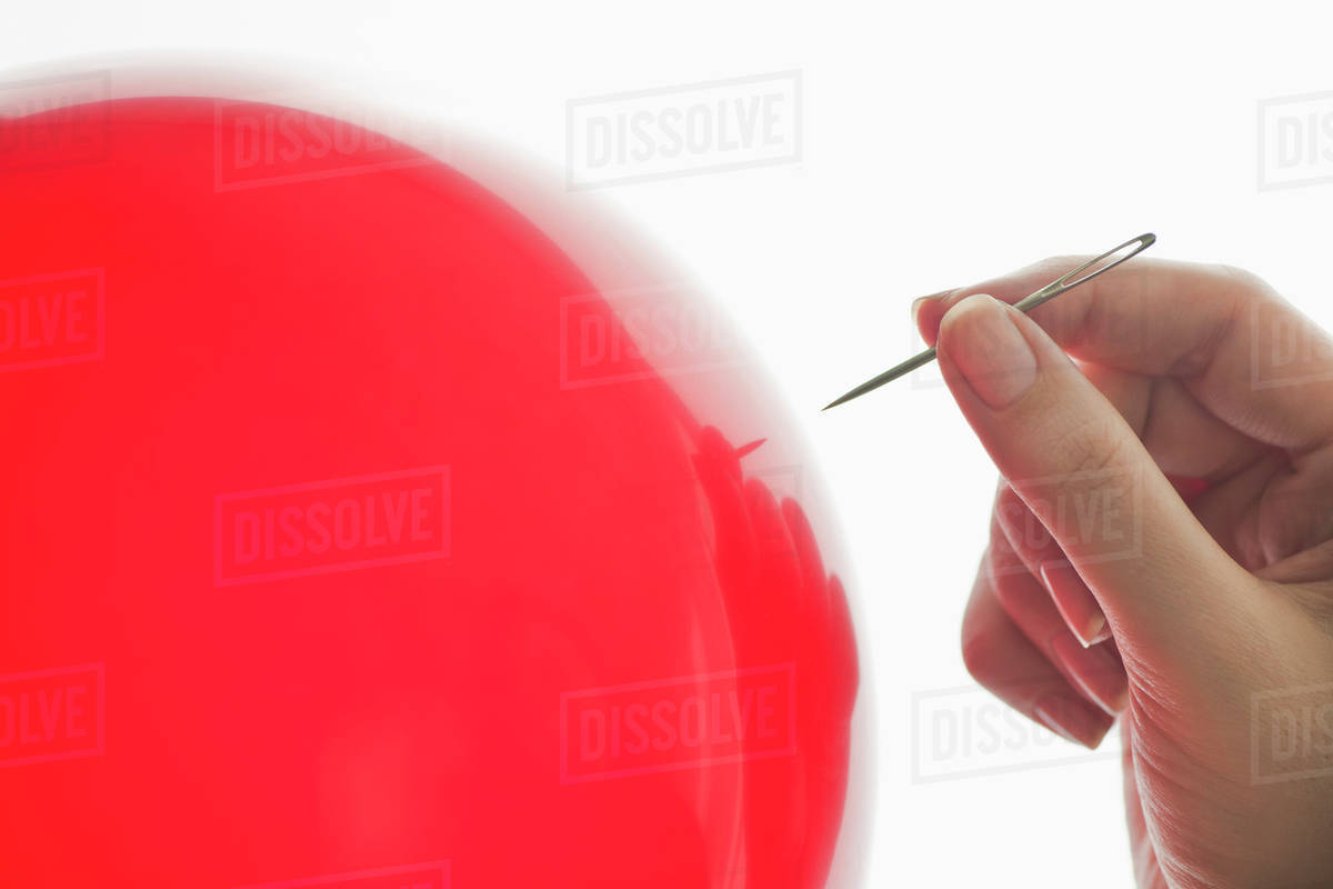 Studio shot of woman holding needle close to red balloon - Royalty-free ...