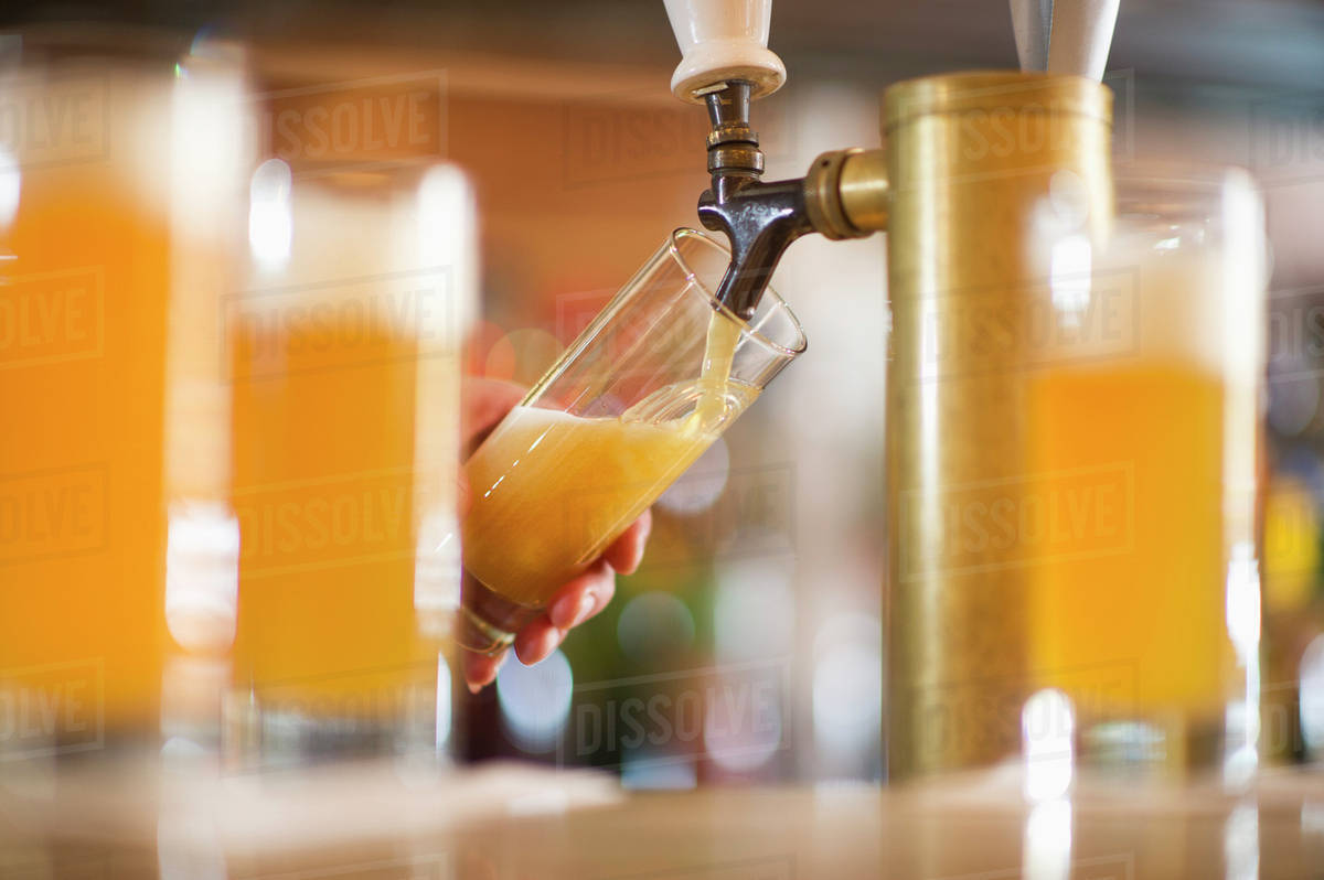 Barman poring beer from beer tap - Stock Photo - Dissolve
