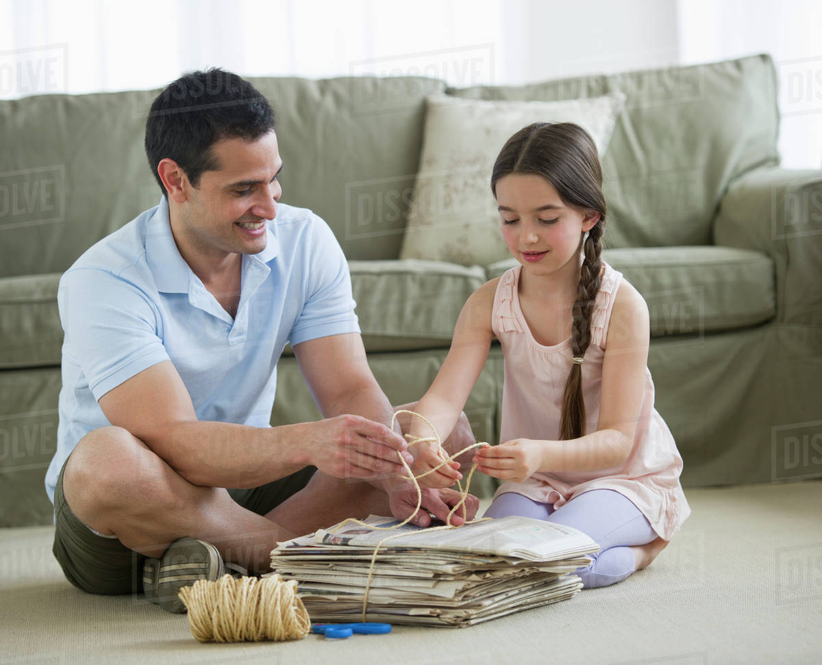 Father and daughter (8-9) wrapping up wastepaper bundle - Stock Photo ...
