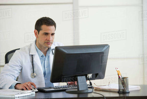 Doctor using computer in office - Stock Photo - Dissolve