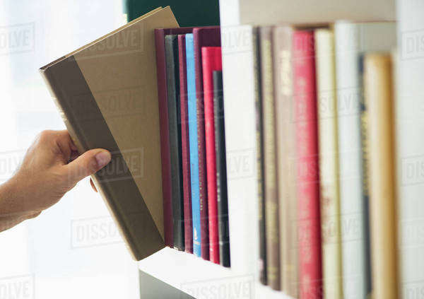 Hand choosing book from shelf - Stock Photo - Dissolve