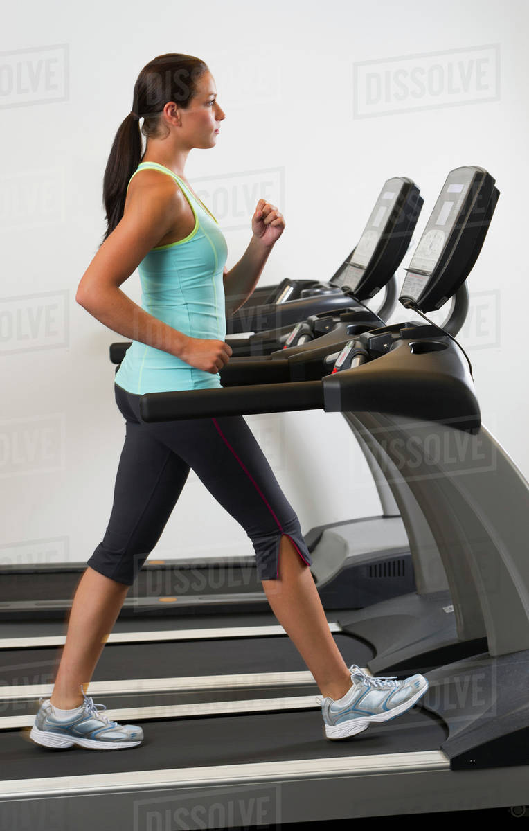 Woman walking on treadmill - Stock Photo - Dissolve
