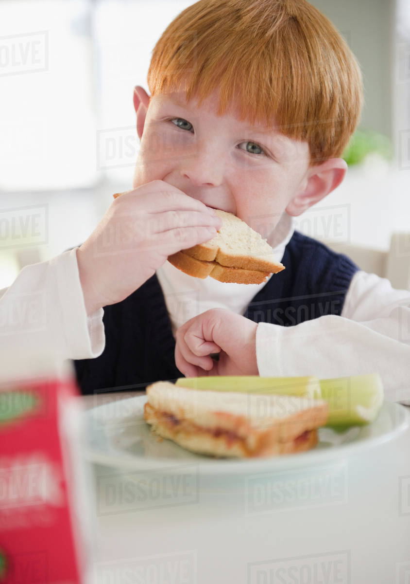 Portrait of boy (8-9) eating sandwich - Royalty-free Stock Photo | Dissolve