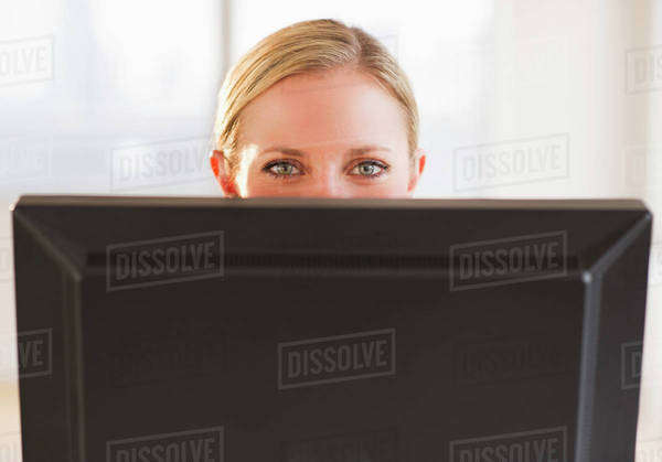 Businesswoman peeking from behind computer - Royalty-free Stock Photo ...