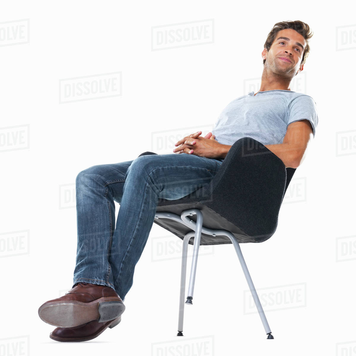 Studio shot of young man balancing on chair - Stock Photo - Dissolve