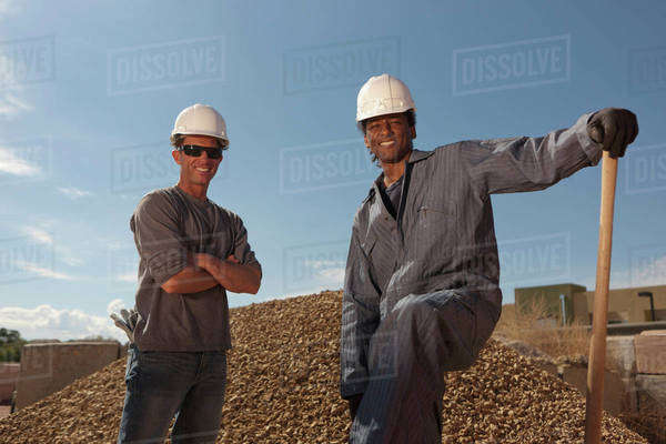 Portrait of two construction workers by rubble on building site ...