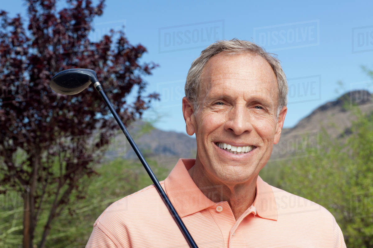 Portrait of senior man holding golf club - Stock Photo - Dissolve